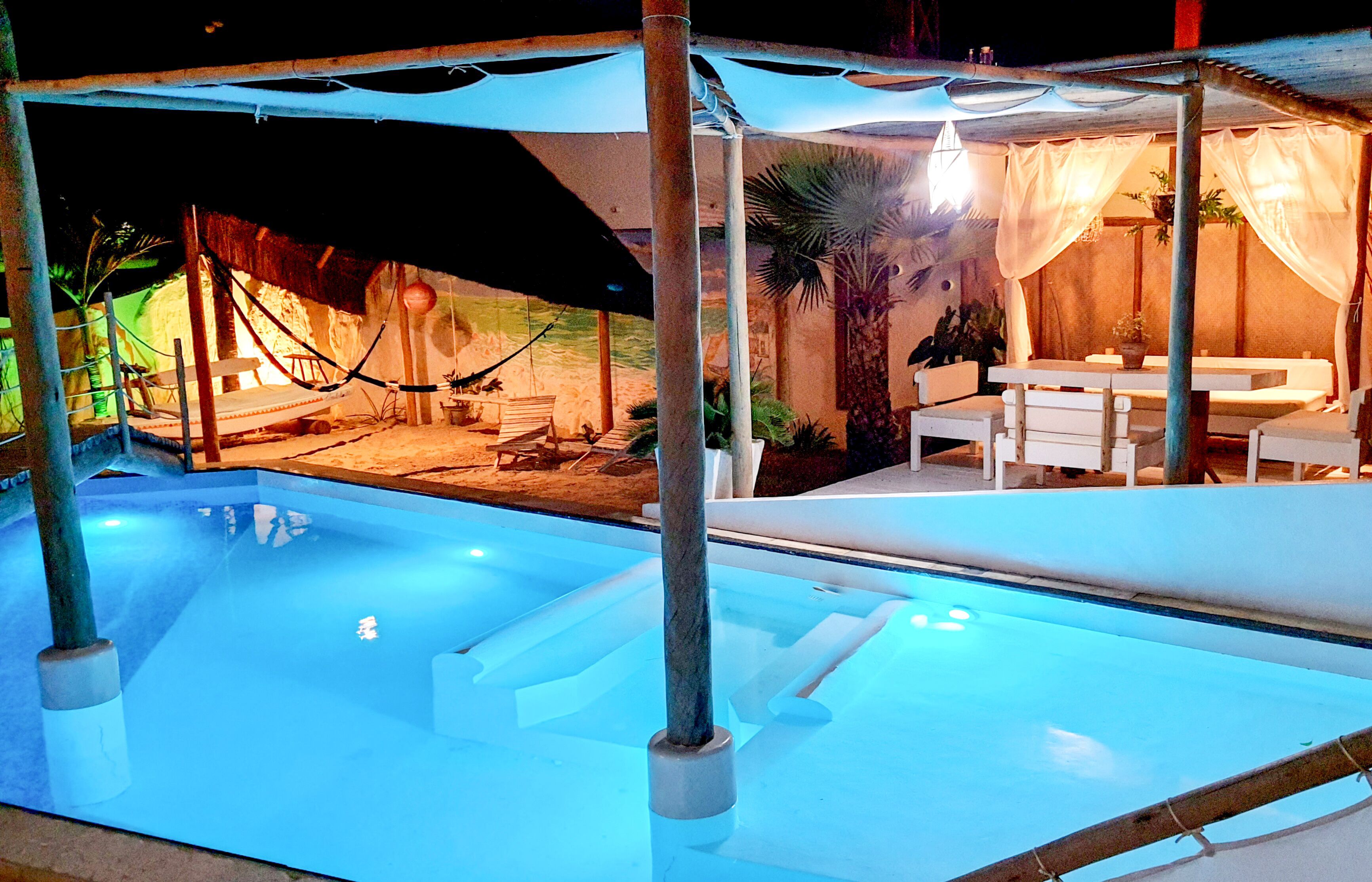 Uma área de piscina com espreguiçadeiras e um espaço de estar coberto.