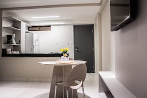 Uma cozinha moderna com área de refeições, armários brancos, bancada preta e uma pequena mesa com uma cadeira.