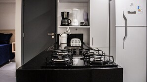 Uma cozinha compacta com fogão a gás, cafeteira e geladeira.