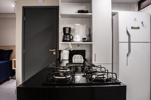 Uma cozinha compacta com fogão a gás, cafeteira e geladeira.
