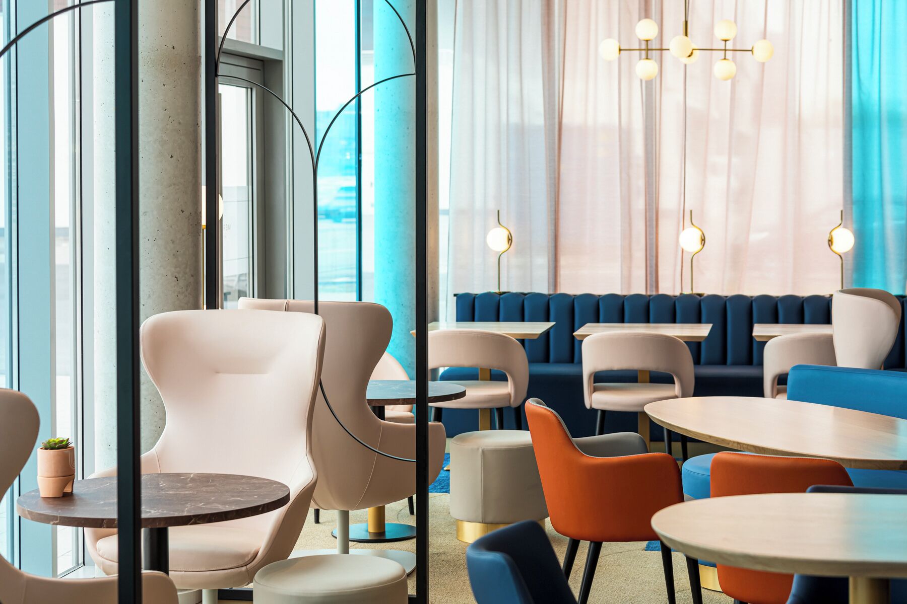 Um café moderno com mesas redondas, cadeiras estofadas e um espaço de bancos azul.