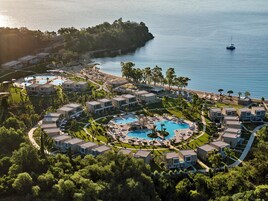 Resort com vários edifícios, área de piscina central e acesso à praia.