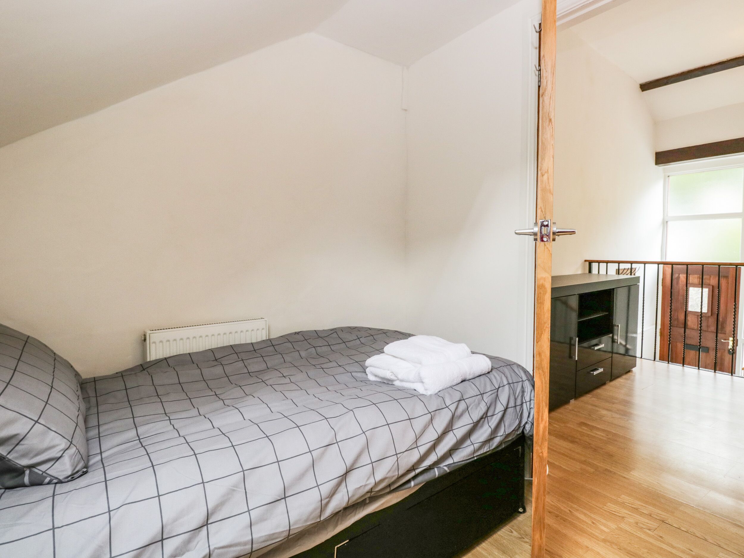 Quarto com cama, radiador e piso de madeira.