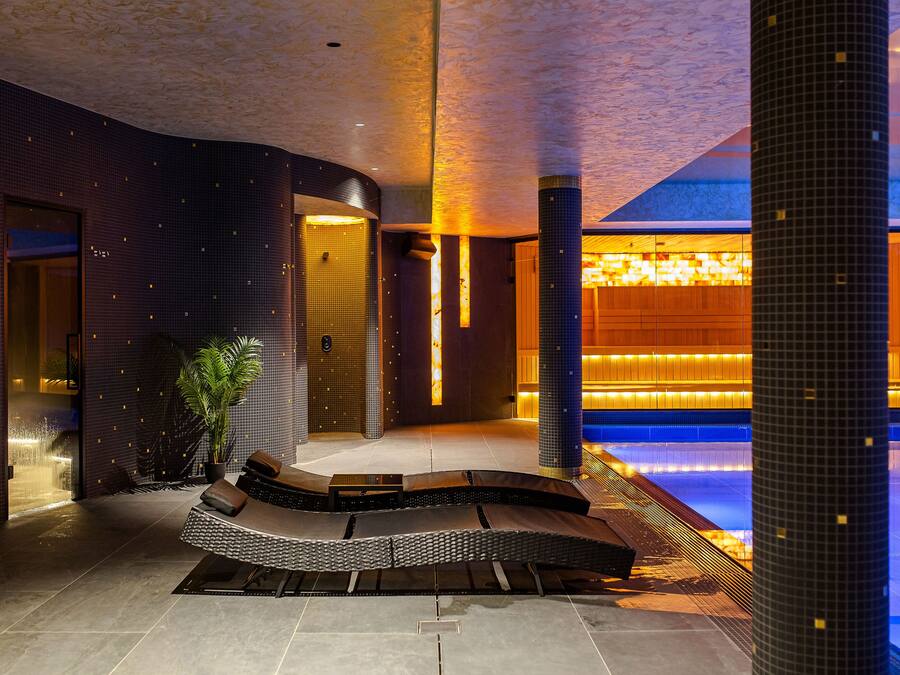 Um lobby moderno com área de estar em curva, piscina e iluminação ambiente acolhedora.