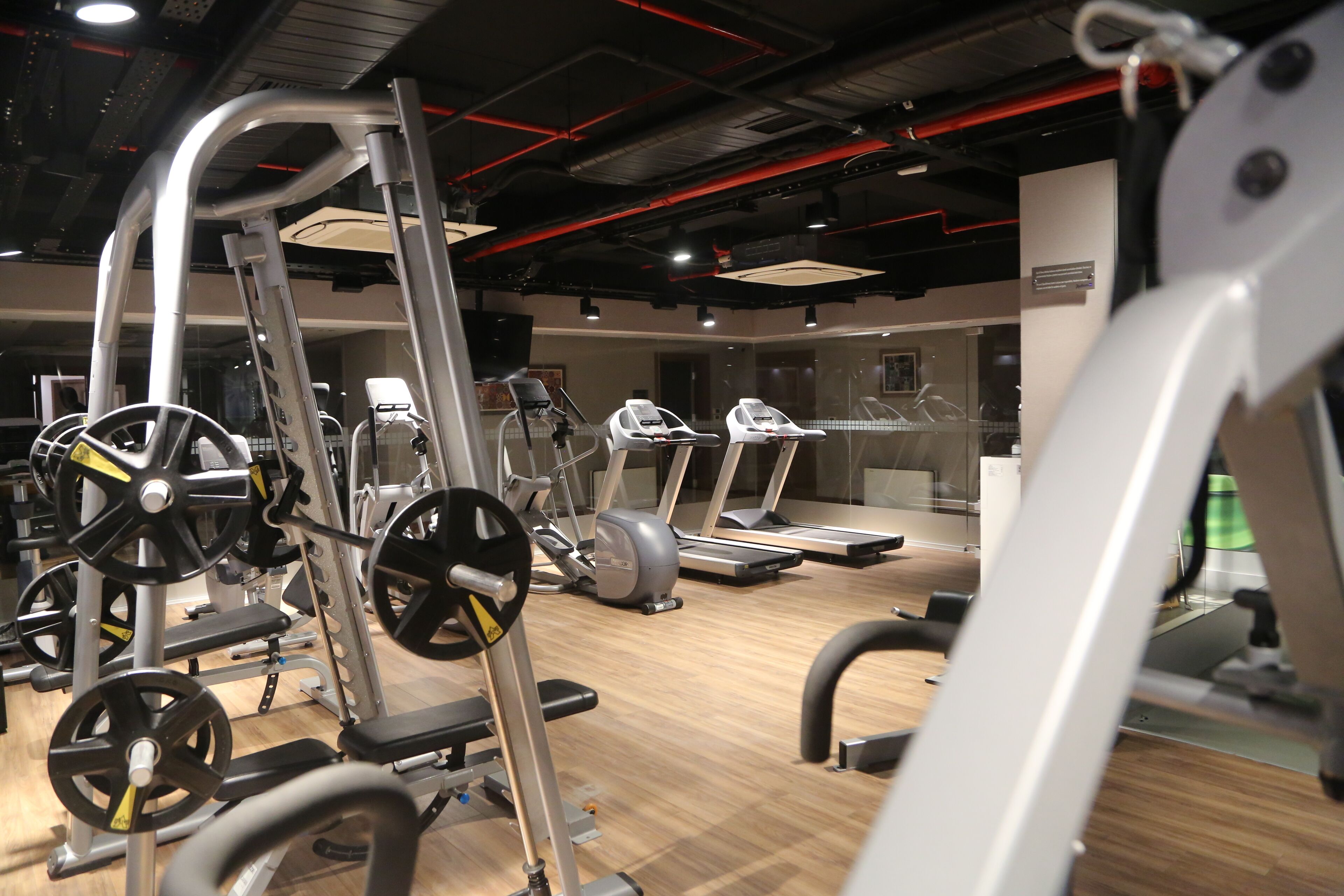 Uma academia com diversos equipamentos de ginástica, incluindo esteiras, aparelhos de musculação e pesos livres.
