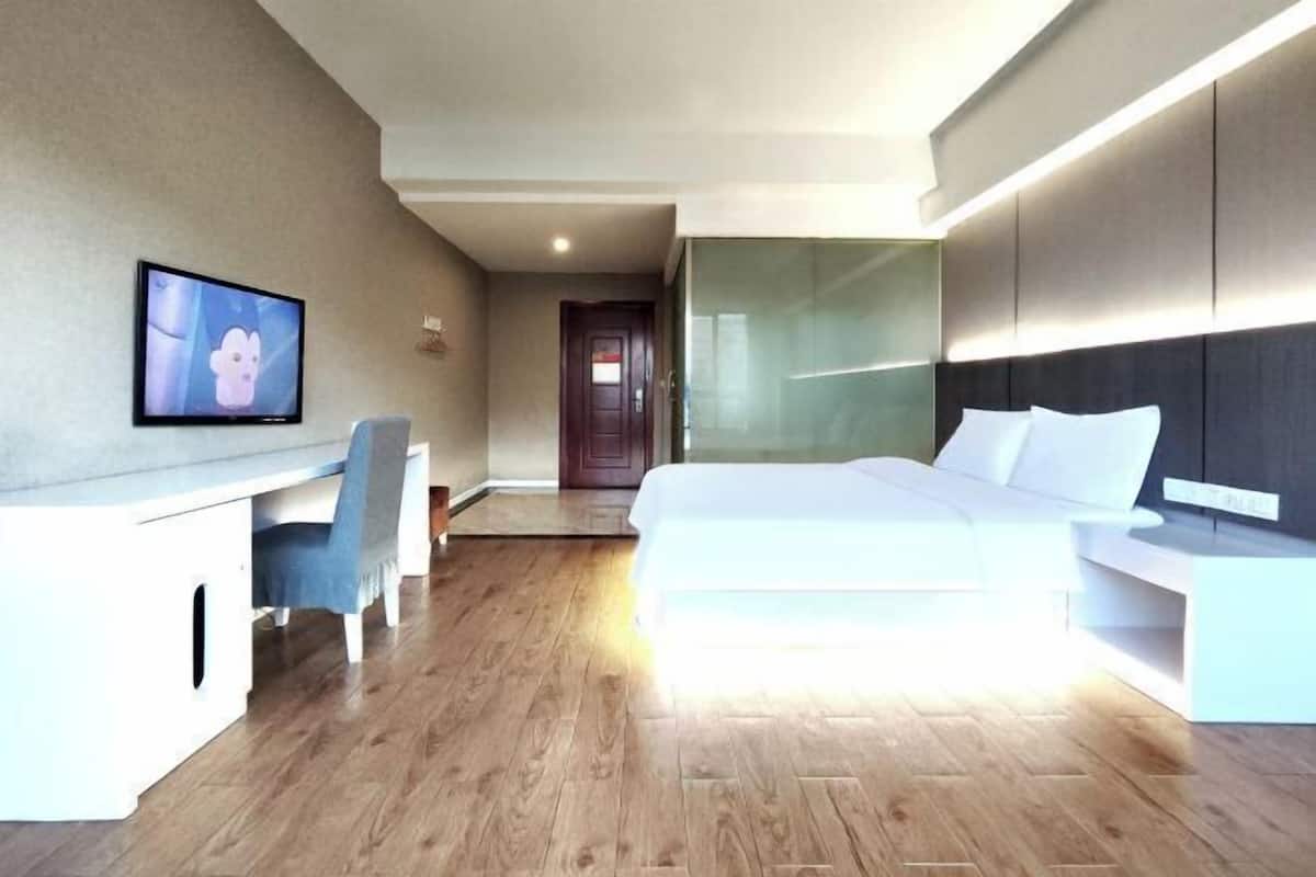 Quarto de hotel moderno com uma cama, uma mesa de escritório e uma televisão.