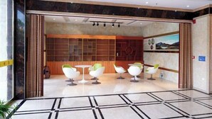 Um lobby moderno com piso de mármore, balcão de recepção de madeira e cadeiras brancas.