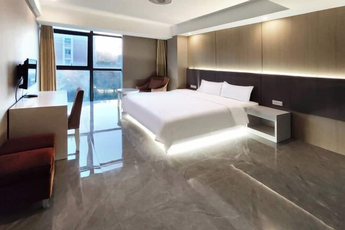 Quarto de hotel moderno com uma cama grande, uma escrivaninha e uma cadeira.