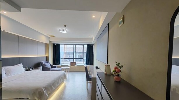Quarto de hotel moderno com uma cama grande, uma escrivaninha e uma área de estar.