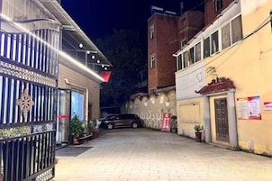 Uma passagem pavimentada com entrada gradeada, um carro estacionado e edifícios com placas e grafites visíveis.