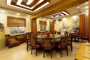 Uma área de refeições com uma mesa redonda rodeada de cadeiras, uma janela com vista e uma parede decorativa com padrão geométrico.