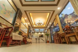 Um hall de hotel com lustre, área de estar e obras de arte nas paredes.