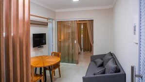 Um espaço compacto com uma mesa de jantar de madeira, um sofá e uma TV fixada na parede.