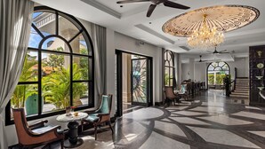Um hall amplo com janelas grandes, um candelabro e vista para o exterior.