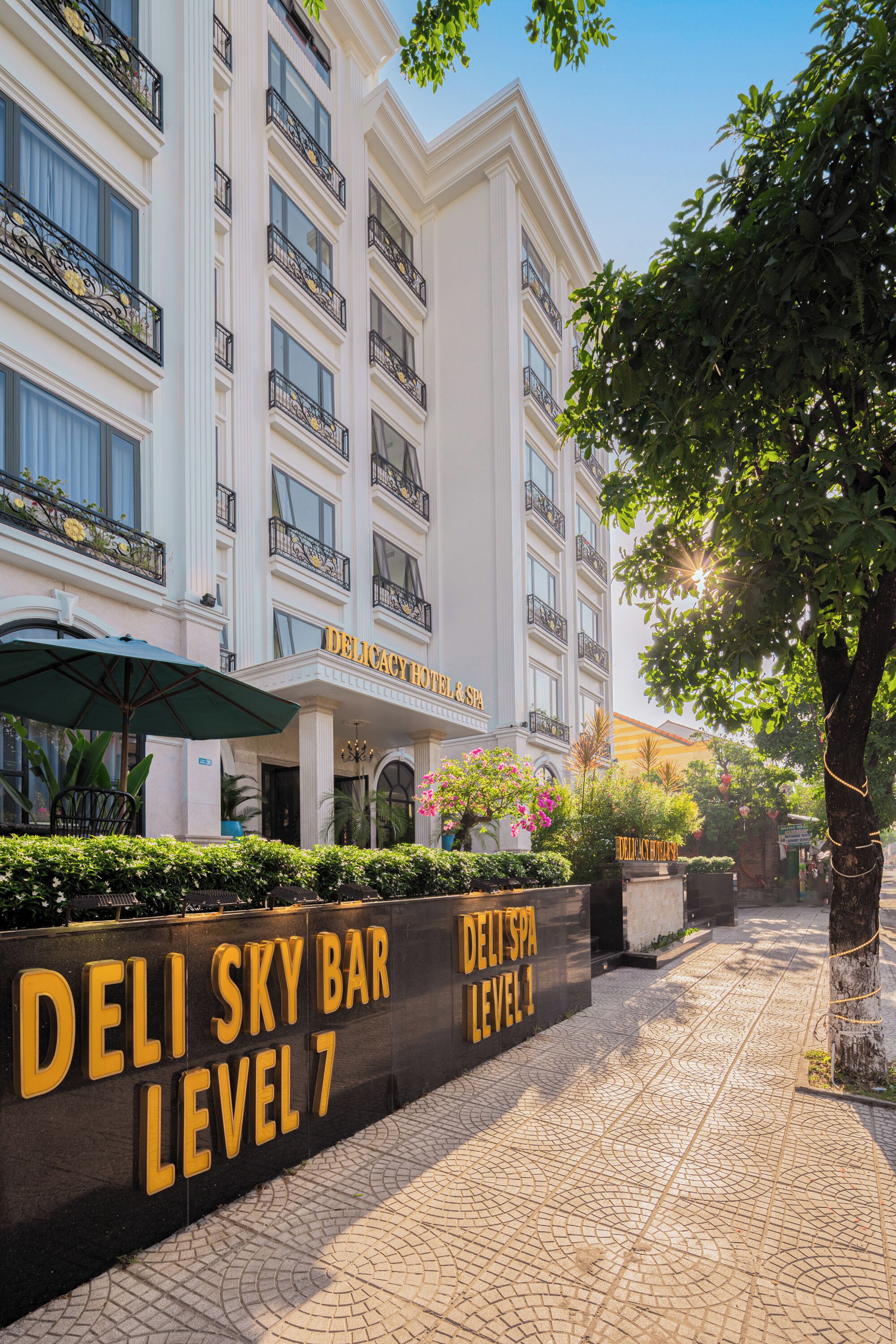 Entrada de um hotel com uma placa indicando 'DELICACY HOTEL & SPA' e 'DELI SKY BAR ANDAR 7'.