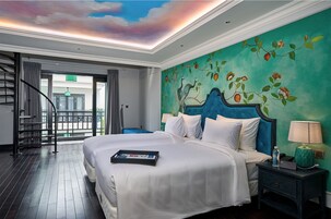 Quarto de hotel com cama, mesa de cabeceira e um mural na parede.