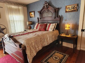 Um quarto tradicional com uma cama de madeira, uma mesa de cabeceira com abajur e um tapete decorativo.