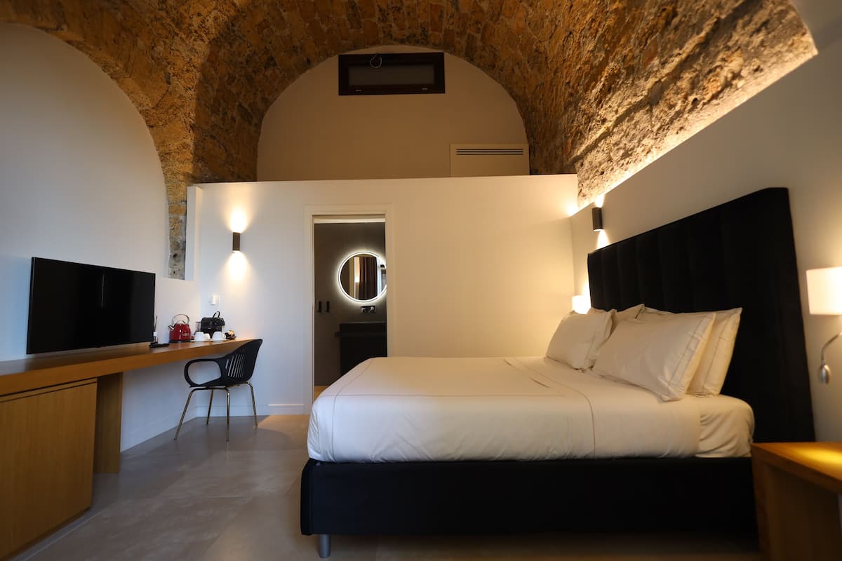 Quarto moderno com cama, mesa de cabeceira e escrivaninha com cadeira.