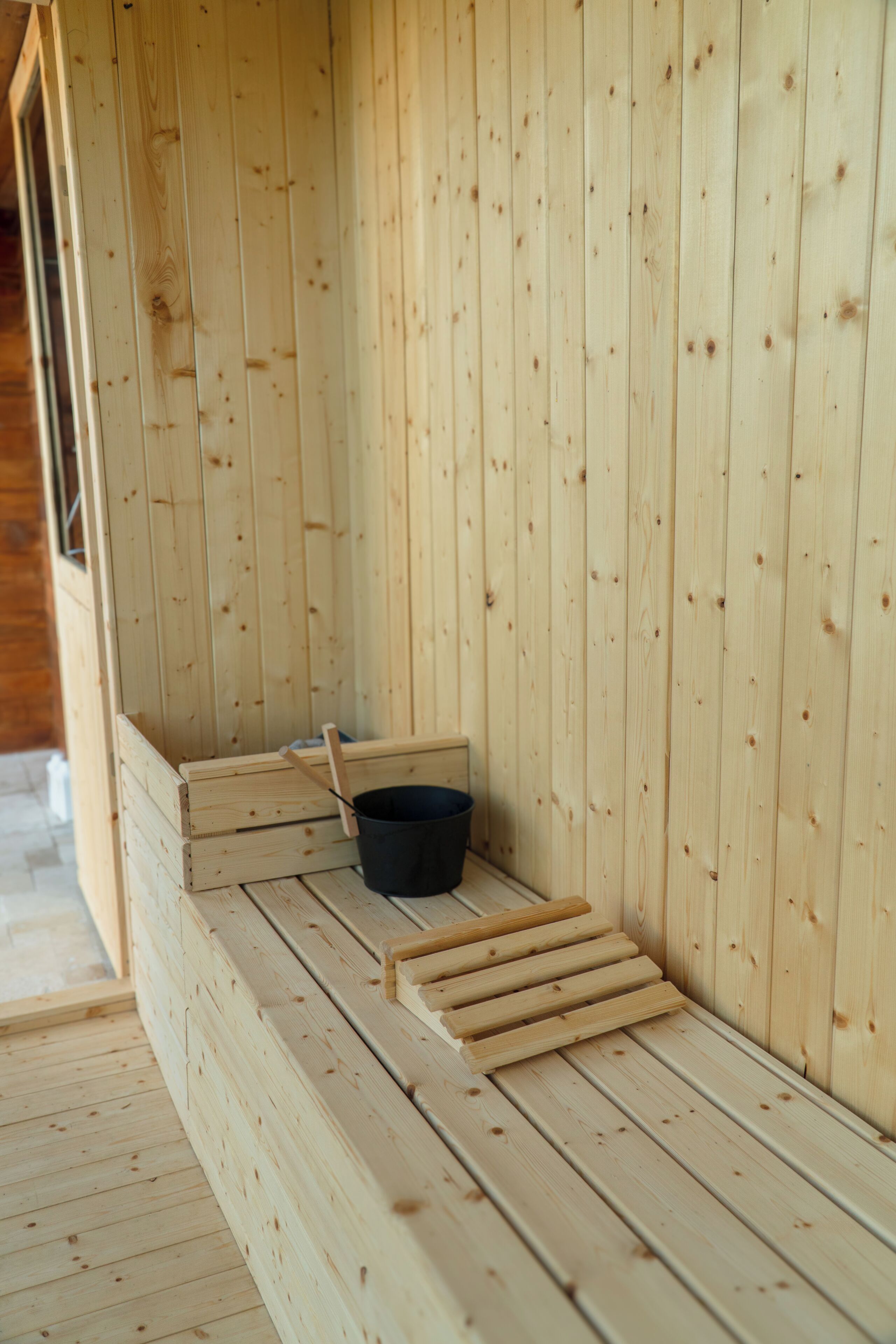Uma sauna de madeira com bancos e um balde.