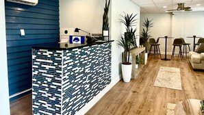 Uma receção com design moderno, um ventilador de teto e uma área de estar com cadeiras e uma mesa.