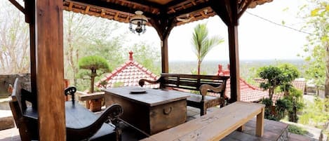 Um gazebo de madeira com uma mesa e bancos, com vista para uma paisagem deslumbrante.