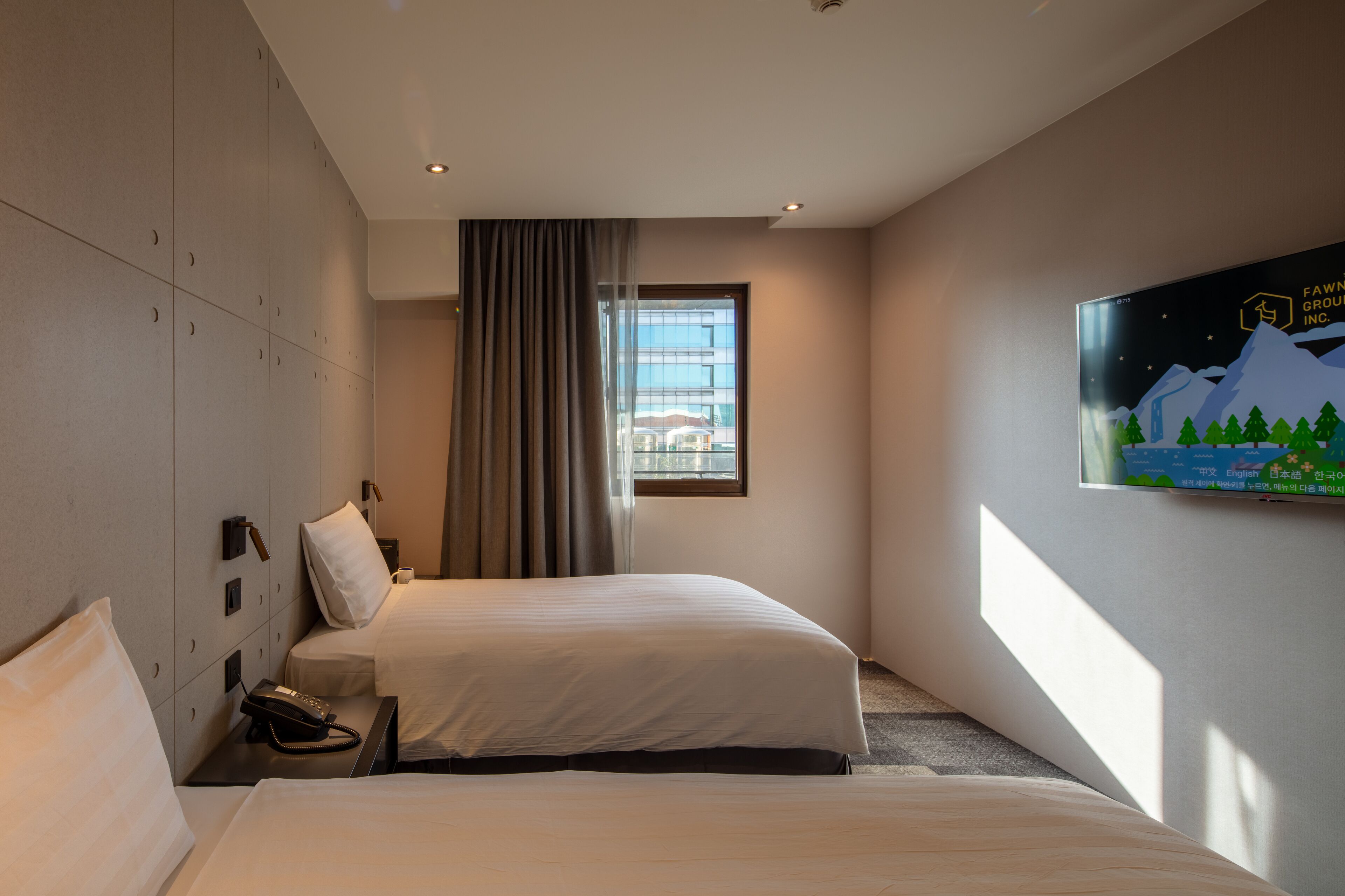 Quarto de hotel com duas camas, uma janela com cortinas, um quadro na parede e um telefone na mesinha de cabeceira.