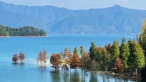 Um lago com montanhas ao fundo e árvores em primeiro plano.