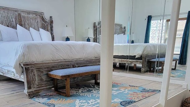 Quarto moderno com claraboia, uma cama grande, um banco e escada com iluminação integrada.