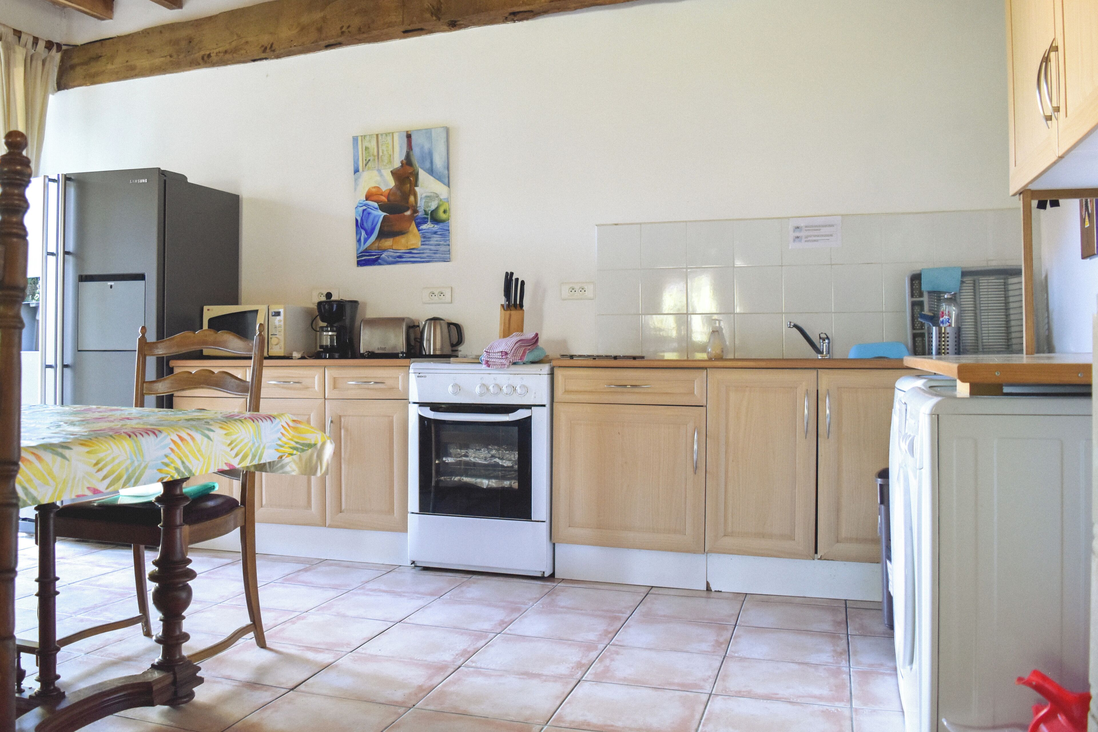 Cozinha equipada com geladeira, fogão, micro-ondas e armários de madeira.