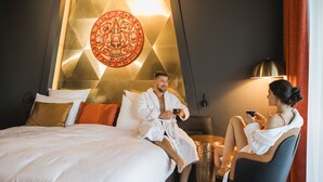Quarto de hotel com uma cama, uma obra de arte na parede, uma mesa de cabeceira e um abajur.