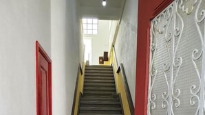 Uma escadaria com uma porta vermelha e um chão estampado que dá acesso a um quarto.