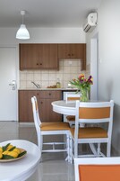 Uma cozinha moderna com armários de madeira, uma mesa de jantar branca com duas cadeiras e um vaso de flores sobre a mesa.