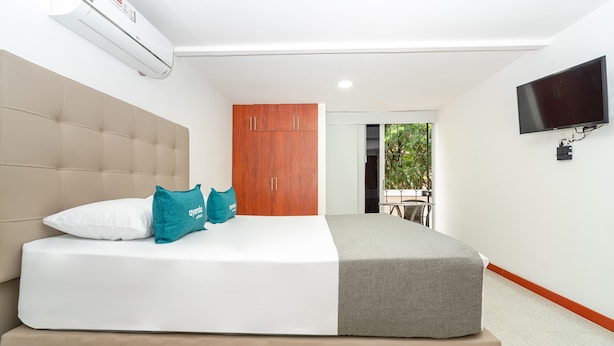 Quarto de hotel moderno com uma cama grande, um guarda-roupa de madeira, uma televisão e um ar condicionado.