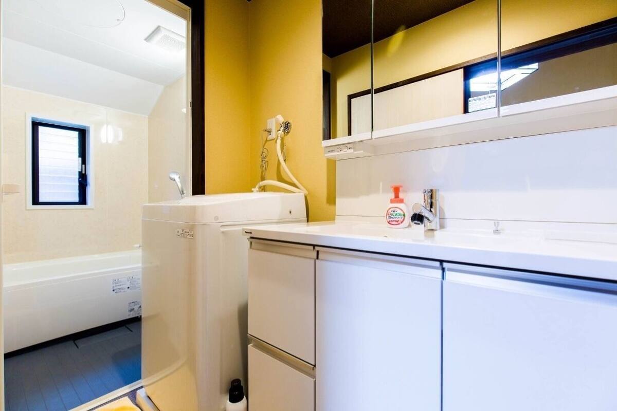 Casa de banho moderna com lavatório branco, espelho e porta-toalhas.