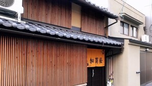 Um edifício tradicional com fachada de madeira, telhado de telhas e uma placa com caracteres japoneses.