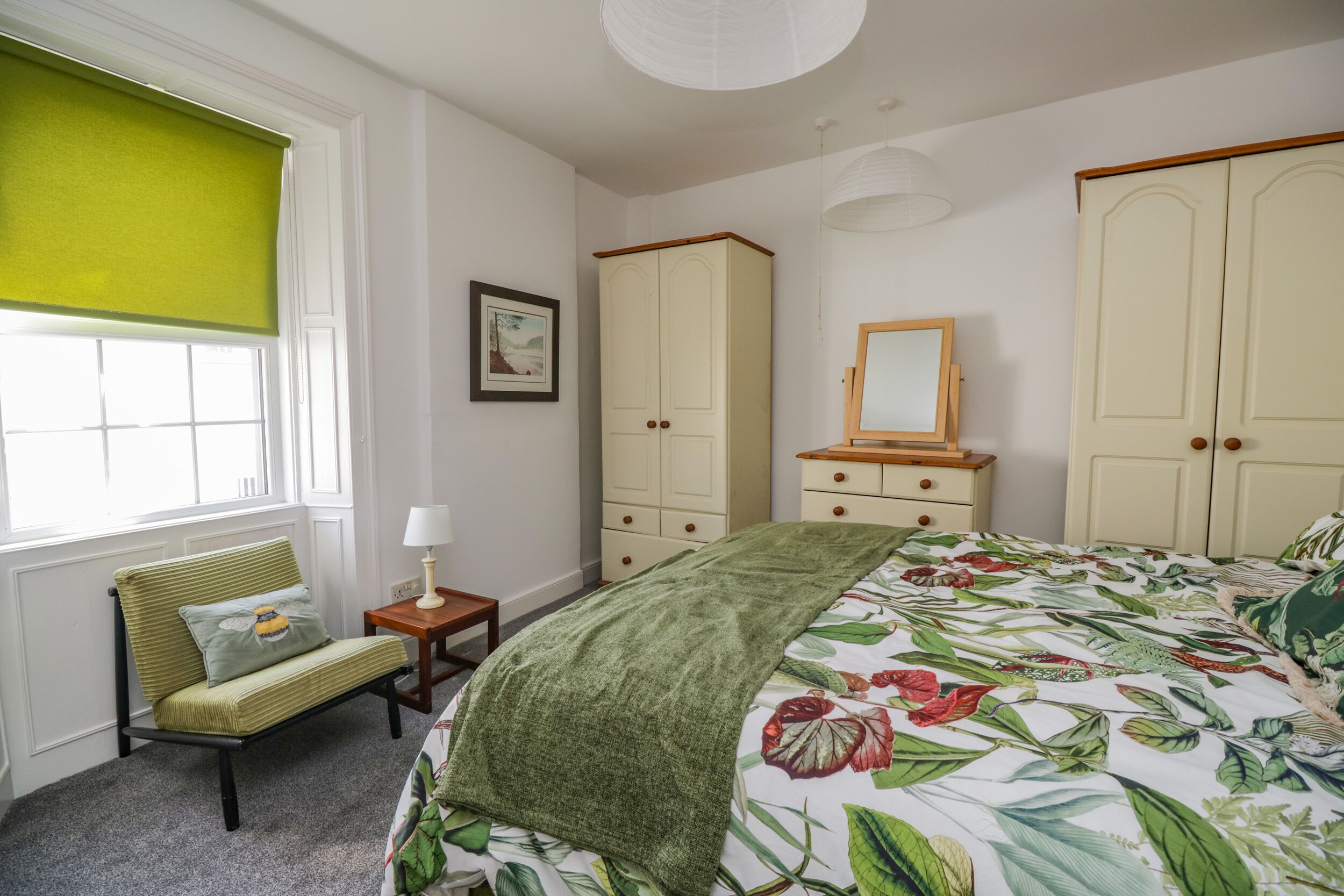 Quarto com cama, cadeira, penteadeira e guarda-roupa.