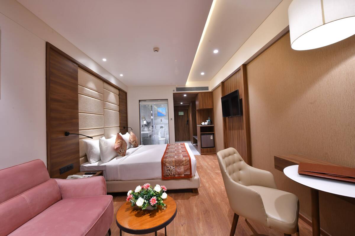 Quarto de hotel moderno com uma cama, um sofá, uma escrivaninha e uma televisão.