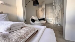 Quarto moderno com cama bem arrumada, uma cadeira e uma banheira.
