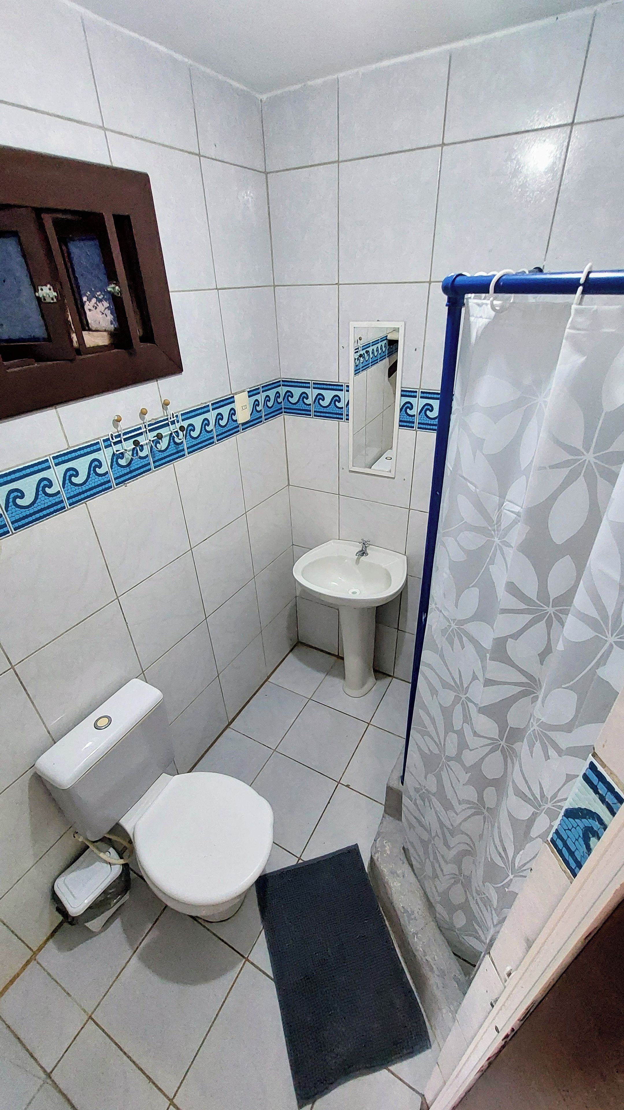 Casa de banho com sanita, lavatório e zona de duche.