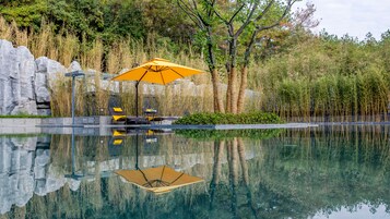 Uma área de piscina tranquila com reflexo límpido, rodeada por formações rochosas e vegetação exuberante.