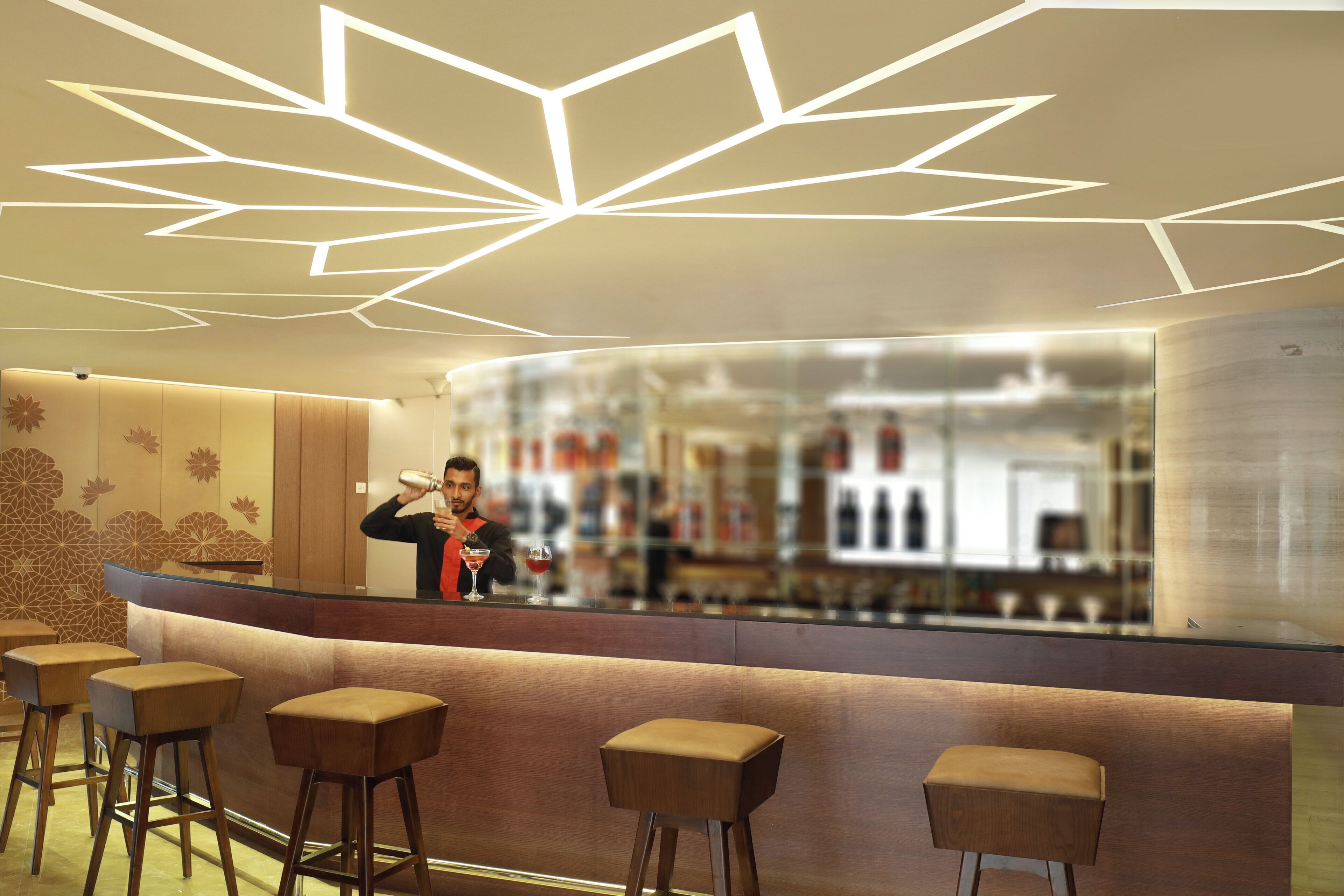 Uma área de bar com banquetas e uma superfície refletora.