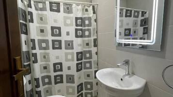 Um banheiro com vaso sanitário, pia e cortina de chuveiro com padrão geométrico.
