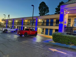 Um motel com vários quartos, estacionamento e uma caminhonete vermelha estacionada em frente.