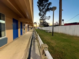 Um edifício com um corredor comprido e reto que leva a uma área gramada com mesas de piquenique.