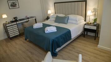 Quarto de hotel com uma cama, duas mesas de cabeceira, uma escrivaninha, uma cadeira e um abajur.