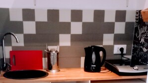 Uma cozinha compacta com pia, cafeteira e geladeira.