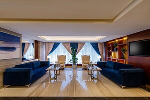 Uma sala de estar moderna com um conjunto de sofás, uma mesa de centro e uma televisão.