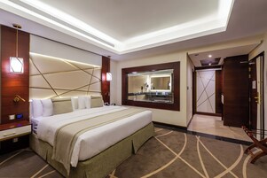 Quarto de hotel moderno com uma cama grande, penteadeira embutida e um espelho amplo.