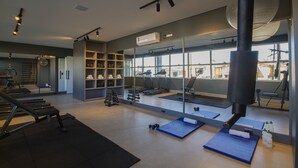 Uma academia moderna com equipamentos de exercício, tapetes e um espelho grande que reflete o espaço.