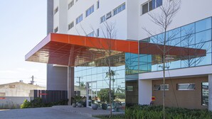 Um edifício moderno com telhado plano, grandes janelas e área de entrada coberta.